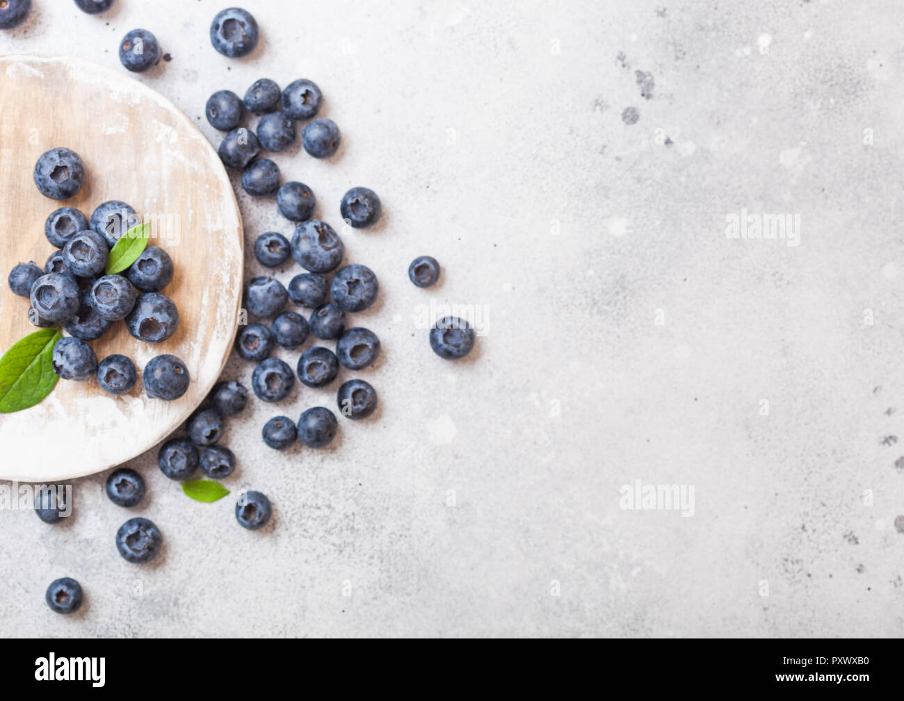 Fresh organic raw blueberries on round wooden board on stone kitchen ...