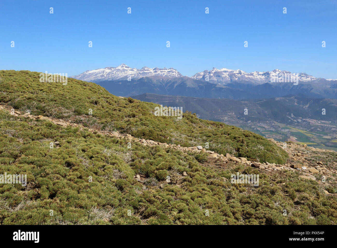 A landscape of snow-clad Pyrenees mountains and a wide valley with blue ...