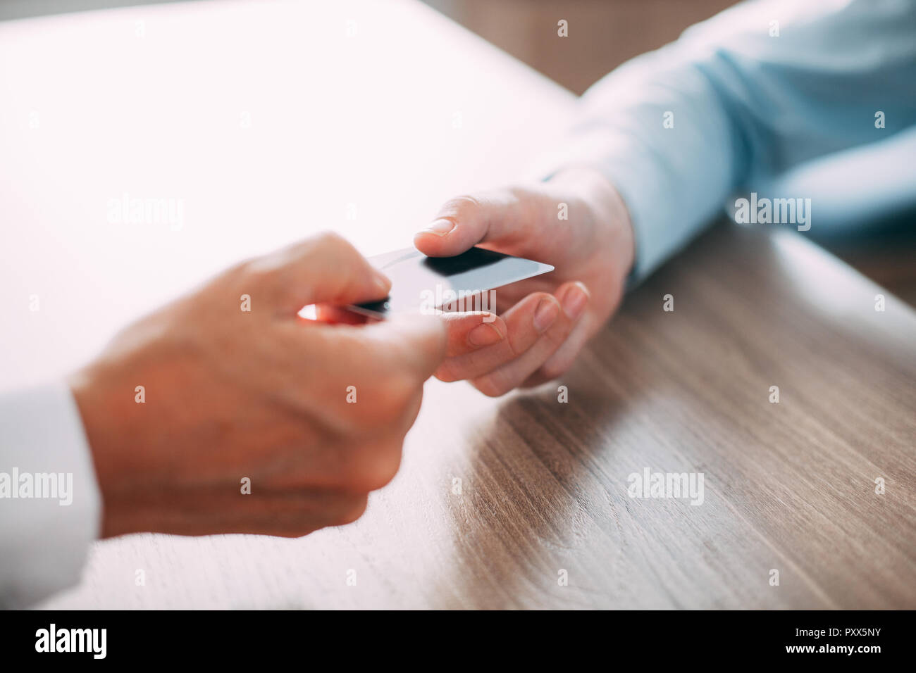 Close-up of male hand giving credit card above table. Unrecognizable ...