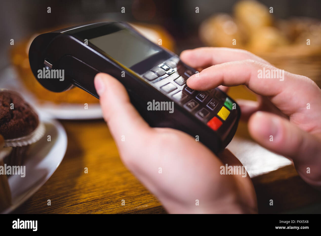Customer making payment through payment terminal at counter in cafe ...