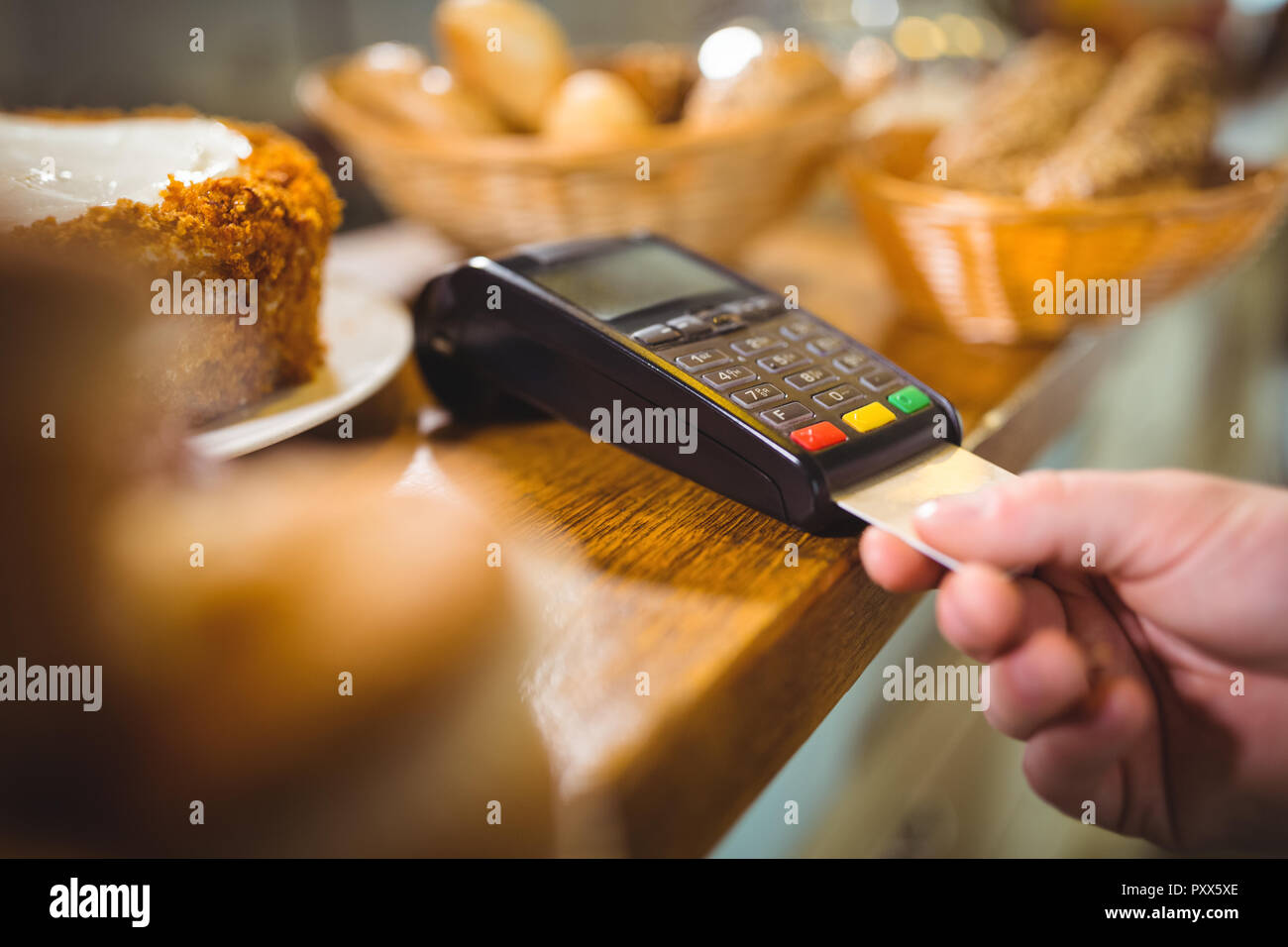 Customer making payment through payment terminal at counter in cafÃƒÂ ...