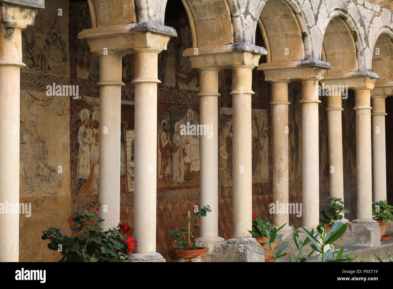 The inner cloister with romanesque arches and medieval frescos during a ...