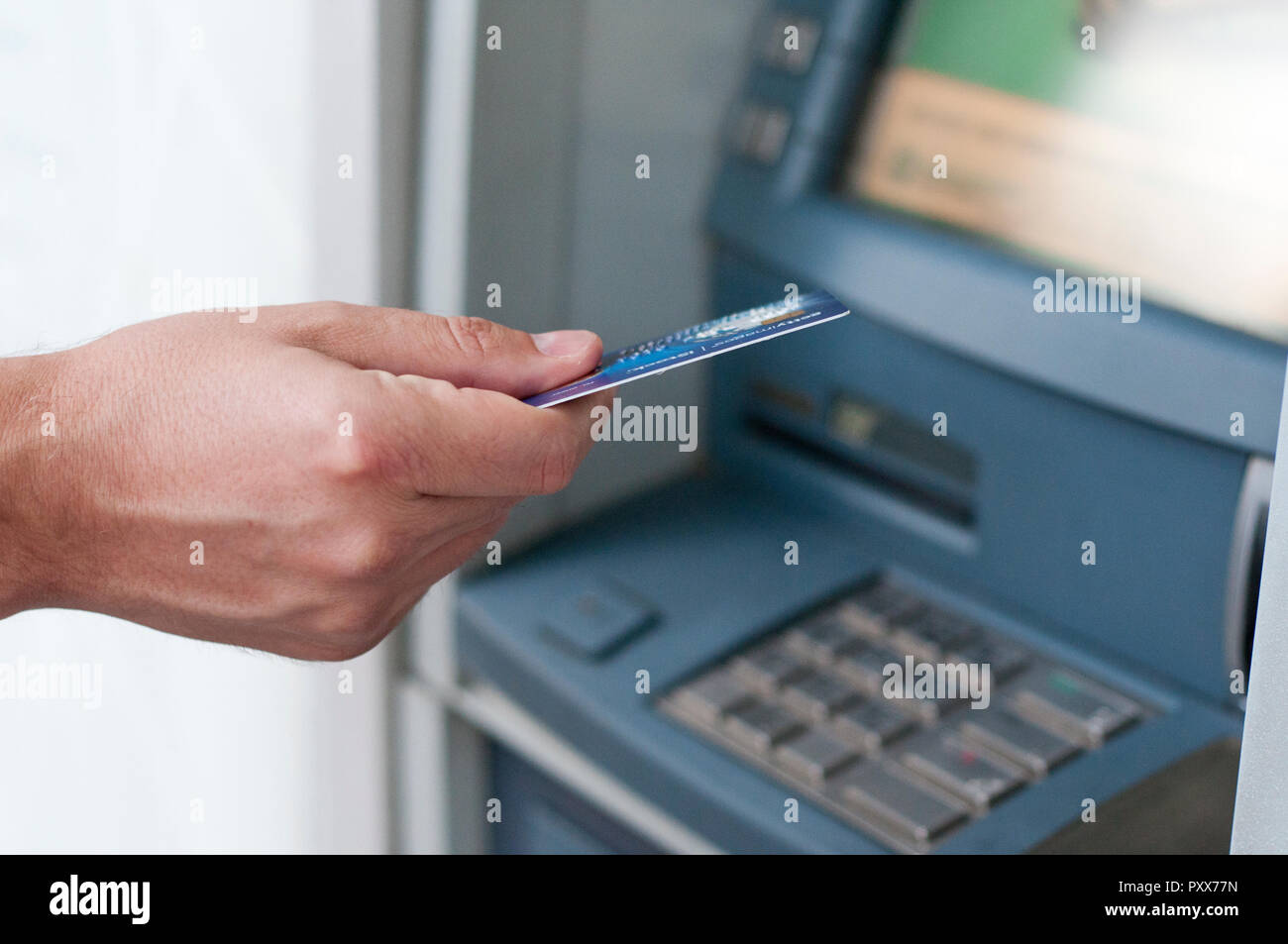 Hand inserting ATM card into bank machine to withdraw money ...