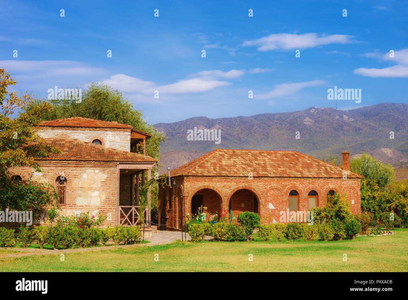 The yard of ancient convent with the blossoming roses and garnet trees ...