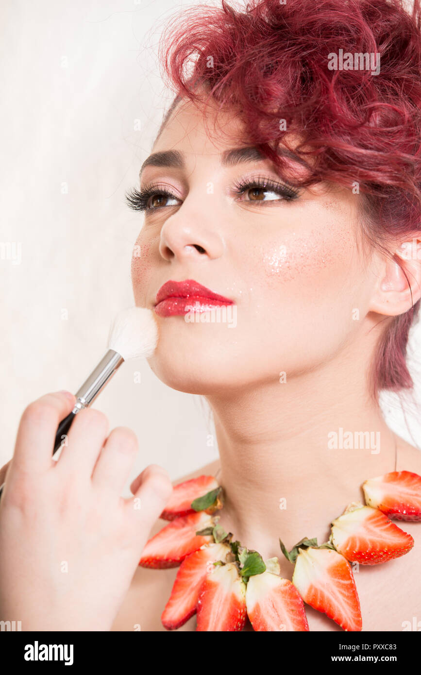 Make-up artist retouching female model's chin with powder brush, on ...