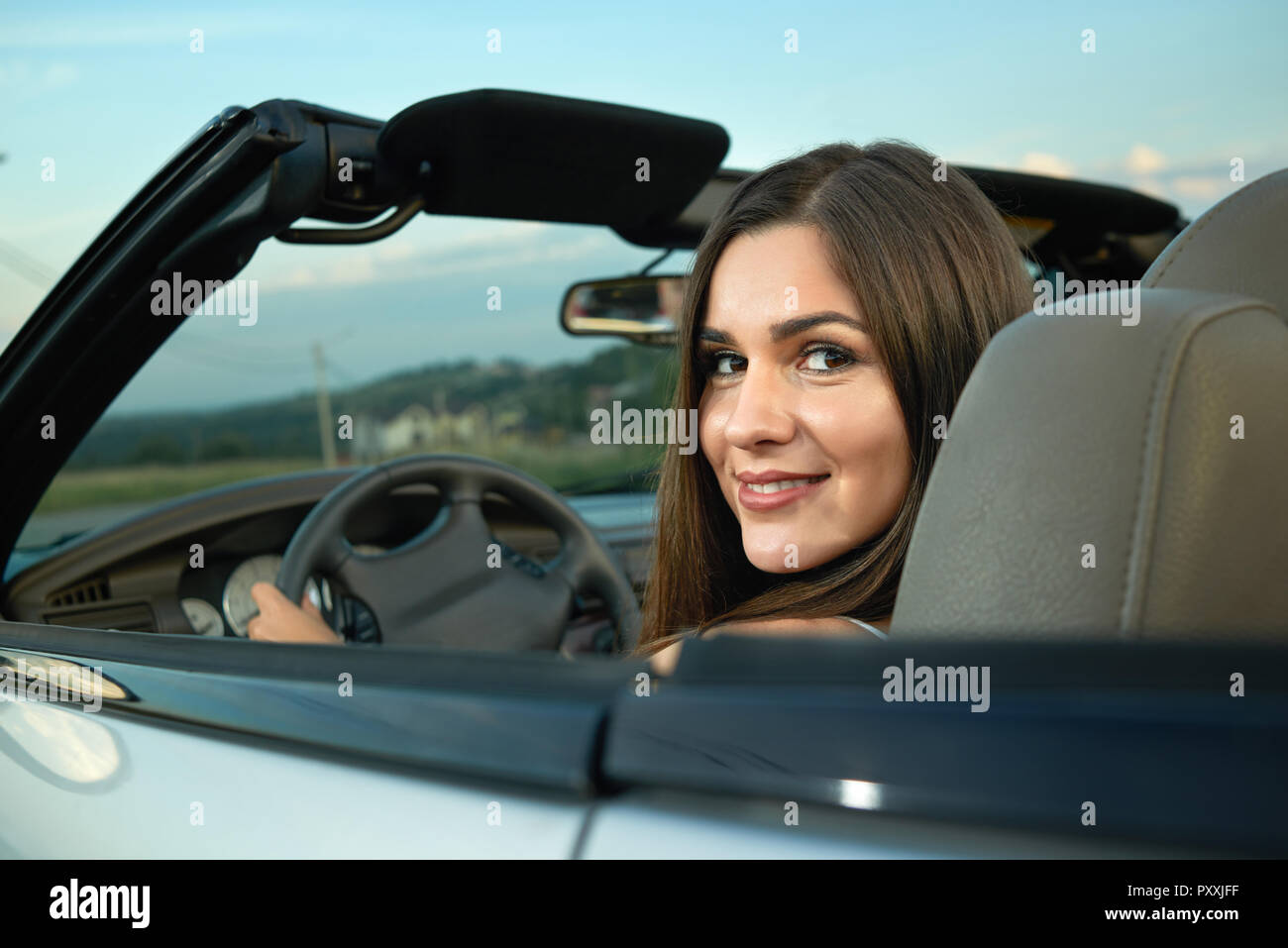 Charming young woman driving car and looking back at camera. Gorgeous ...