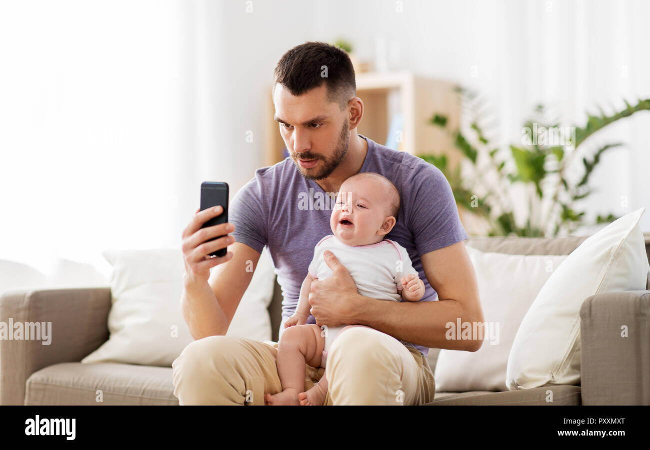 father with crying baby and smartphone at home Stock Photo - Alamy