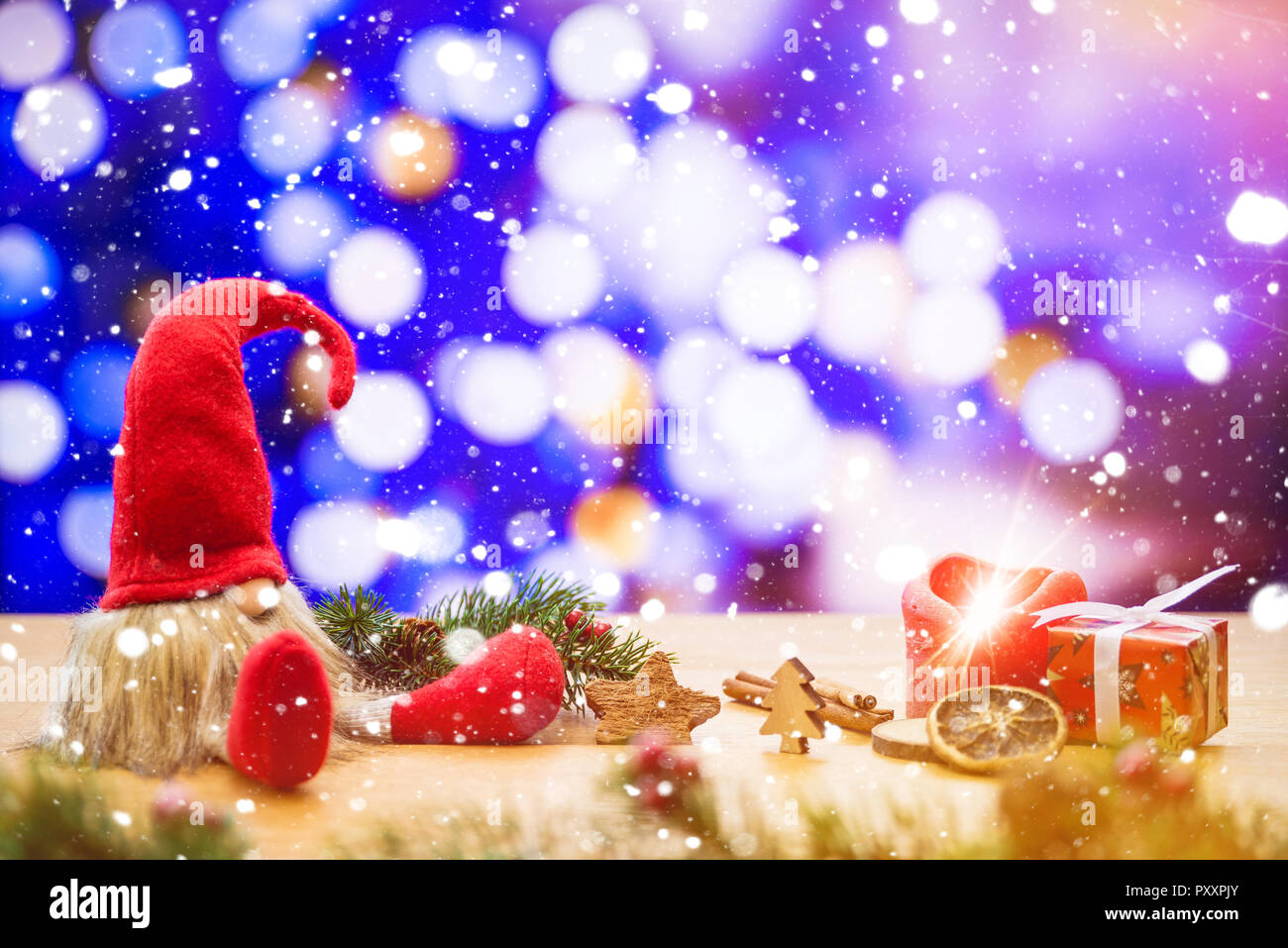 Red sitting christmas elf in falling snow with bokeh lights in ...