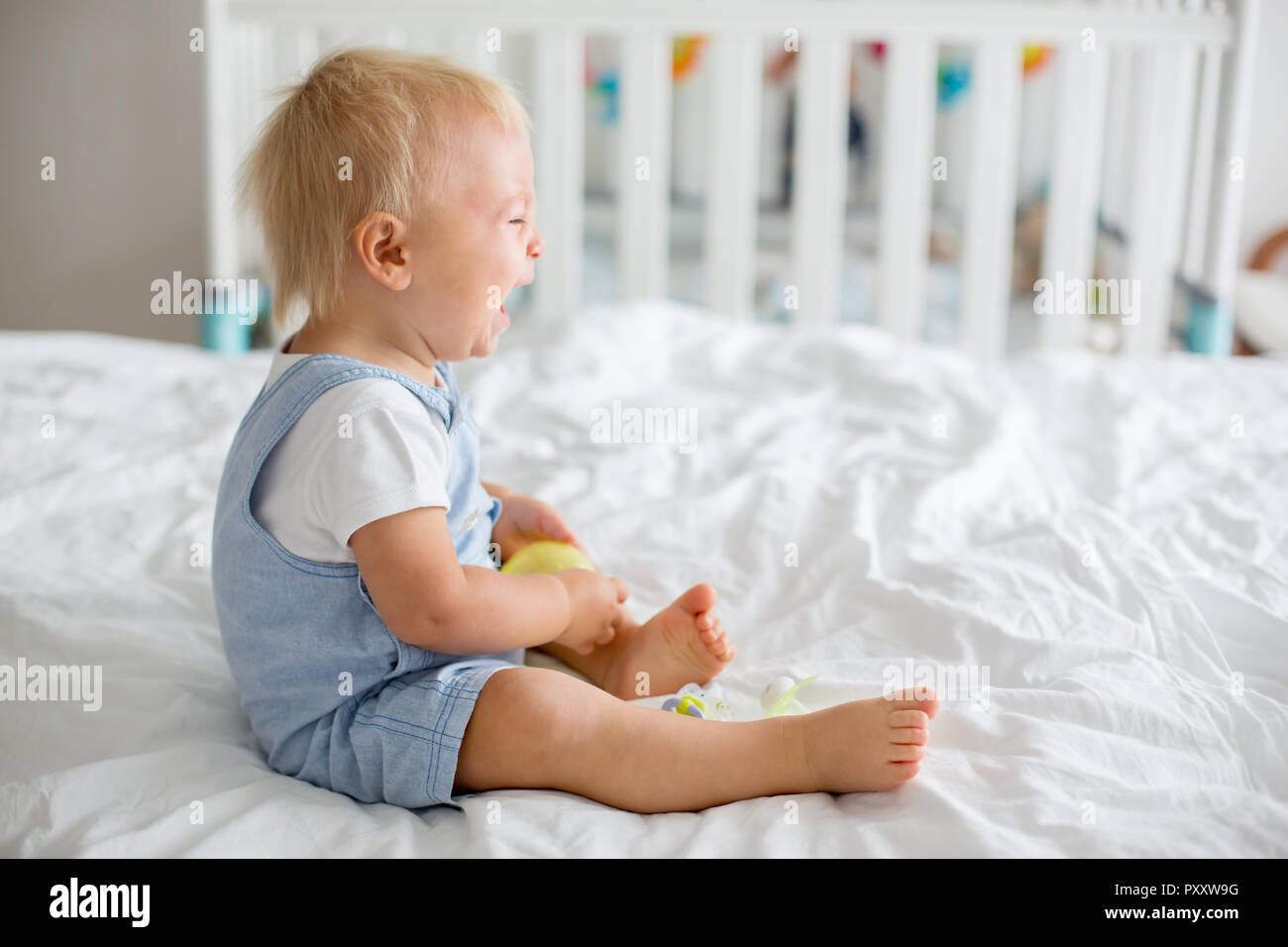Toddler baby boy, playing with dummy, crying unhappy for the pacifier ...