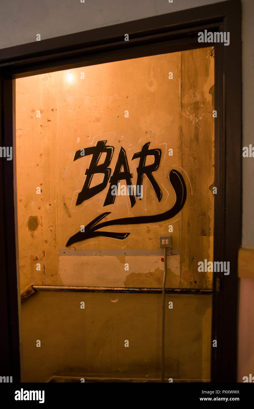 hand painted sign for a bar with an arrow pointing towards the left and ...