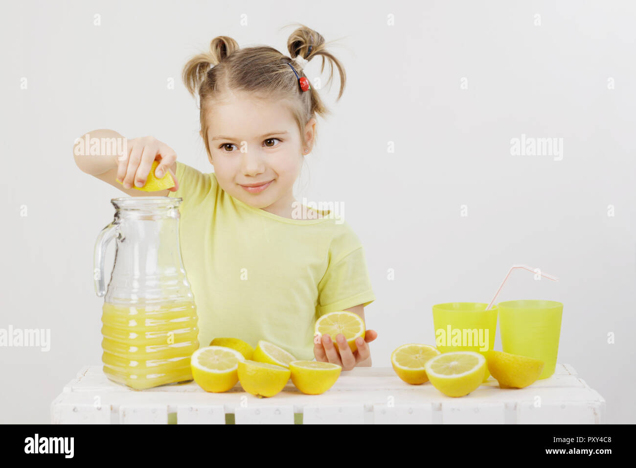 Cute little girl squeezing lemon and making lemonade, "if life gives you lemon, make a lemonade ...