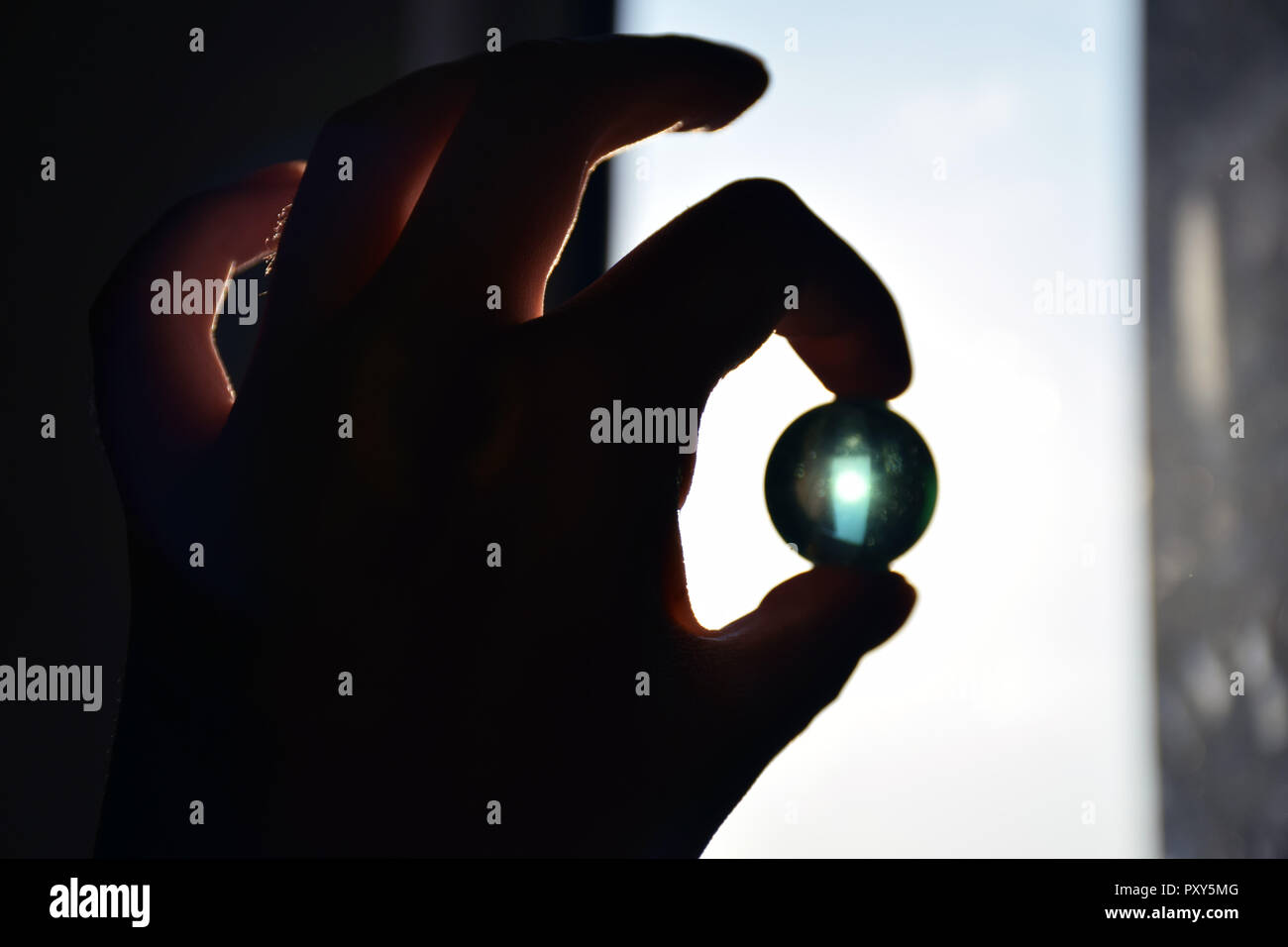 Hand holding a marble ball on the fingers Stock Photo - Alamy