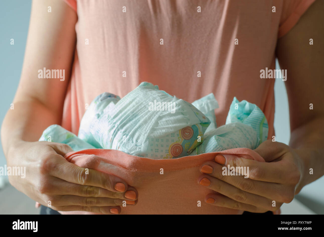 a woman holds in her t-shirt with her hands a lot of used diapers Stock ...