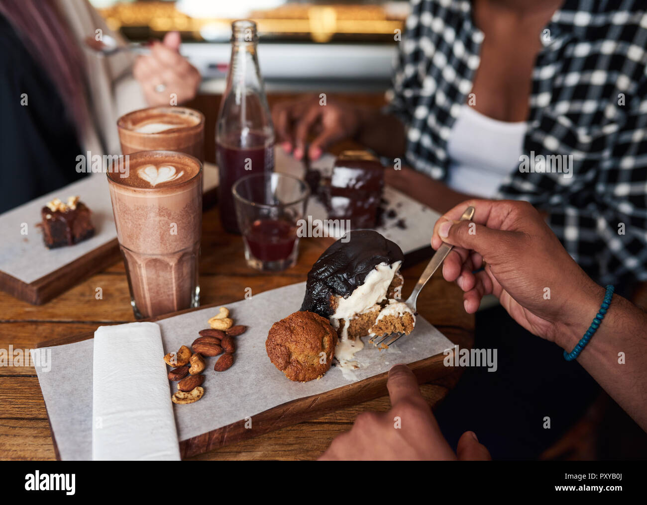 Friends enjoying desserts and coffee together around a cafe table Stock ...