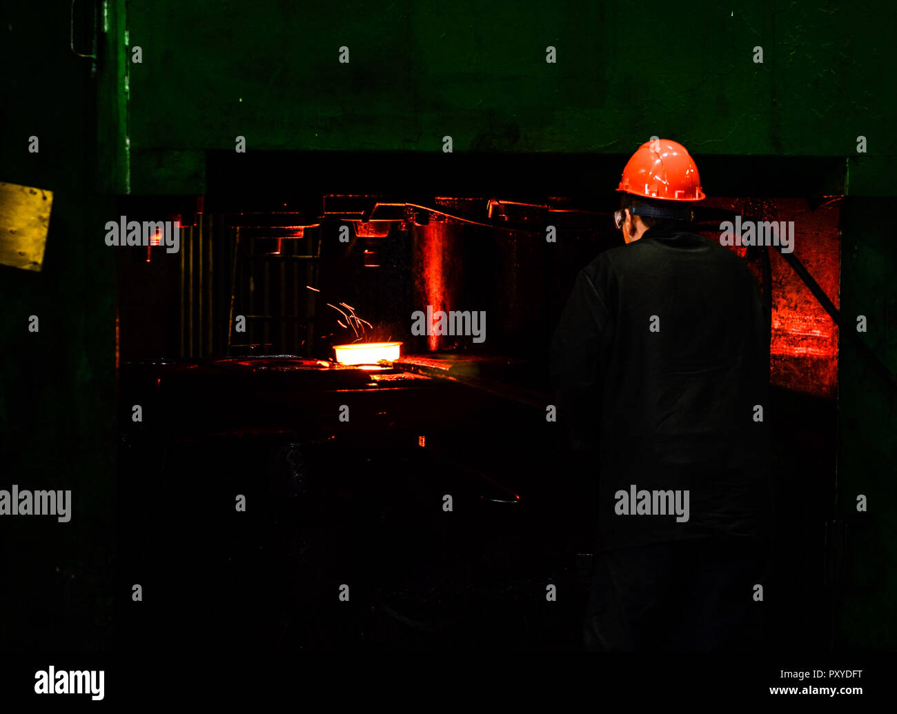 Hot iron in smeltery held by a worker. Iron melting recycling work ...