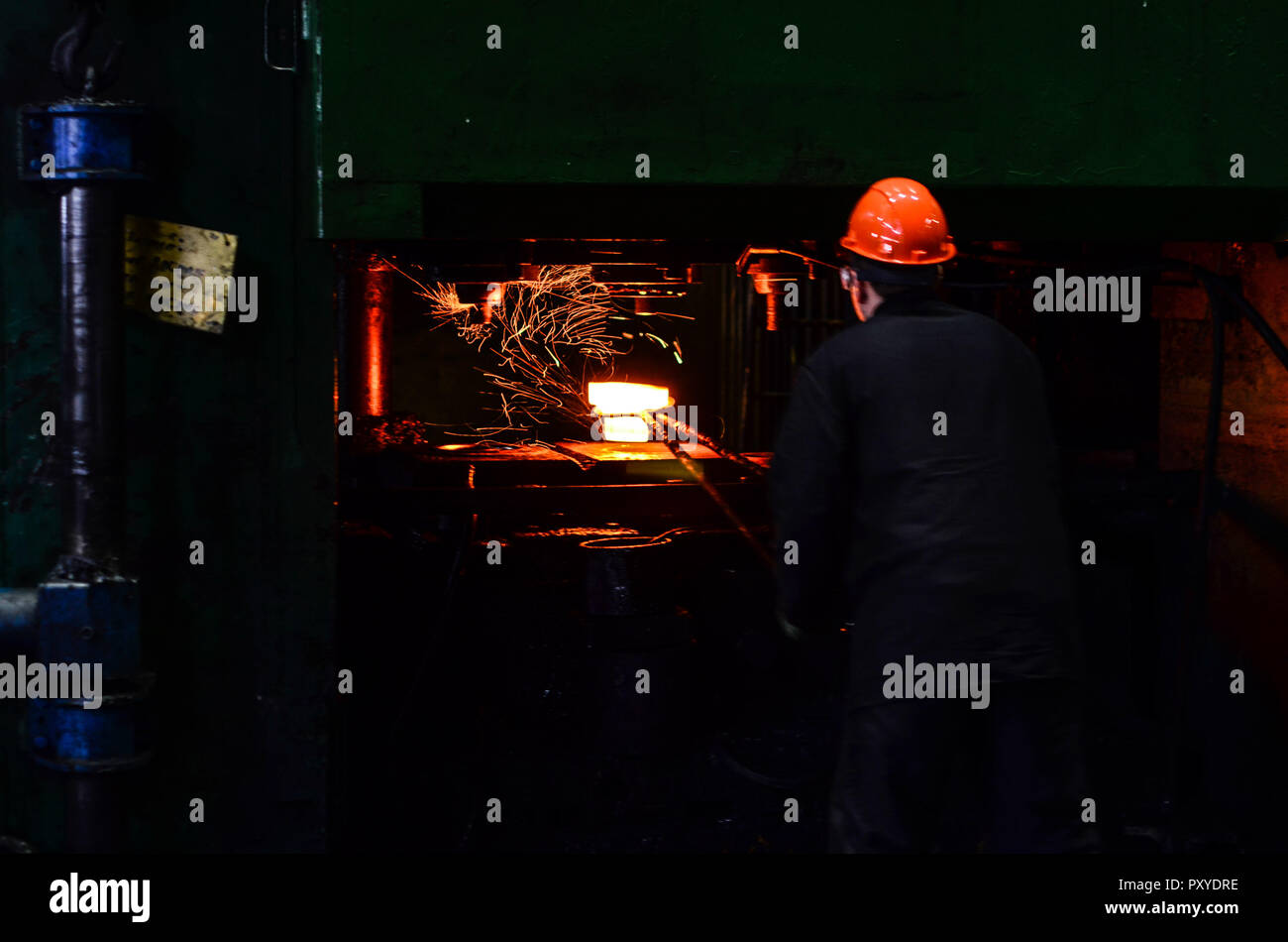 Hot iron in smeltery held by a worker. Iron melting recycling work ...