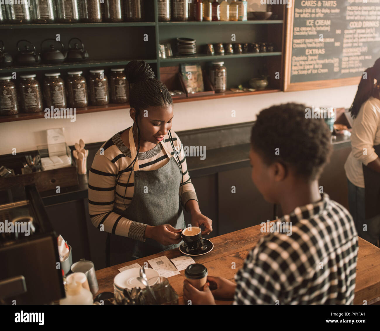 Smiling African barista giving her customer a fresh cappuccino Stock ...