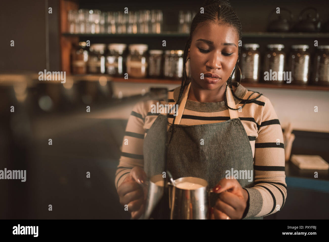 Young African barista making a cappuccino behind her cafe counter Stock ...