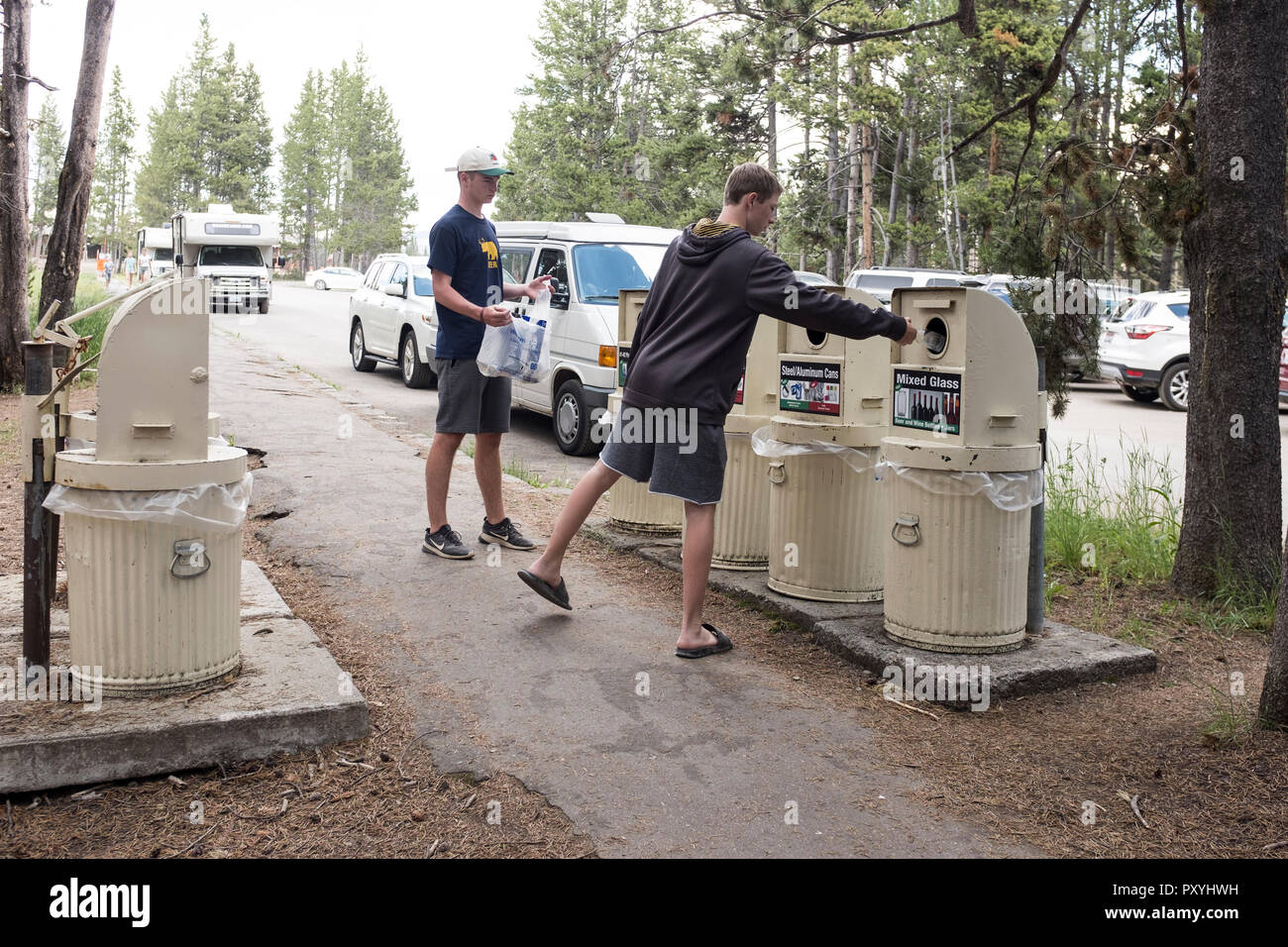 Two young men putting their trash into separate recylcling bins in ...