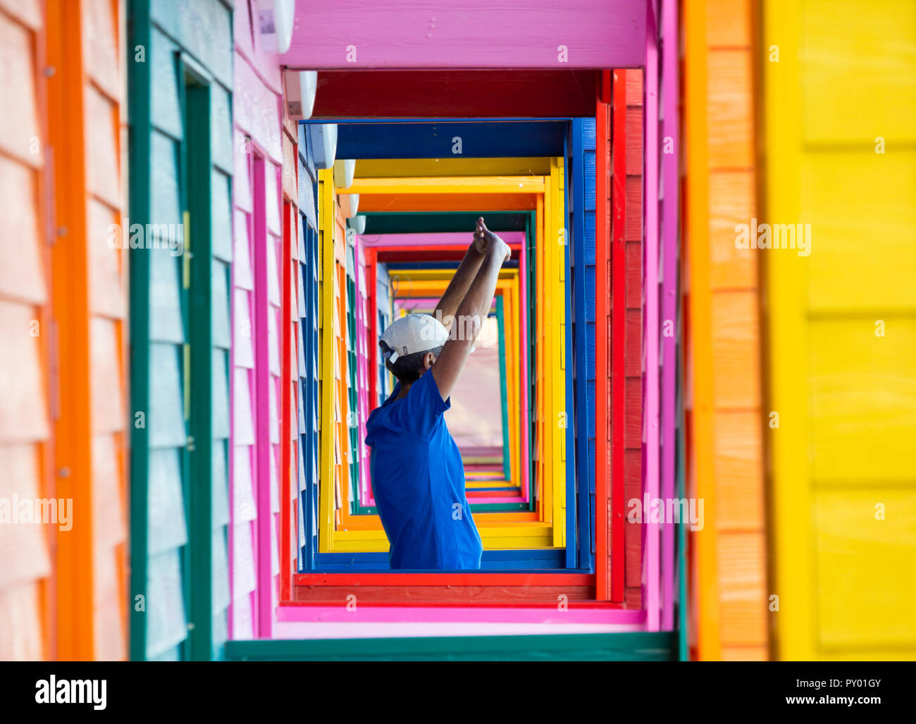Man, male jogger warming up, stretching in doorway of colourful beach ...