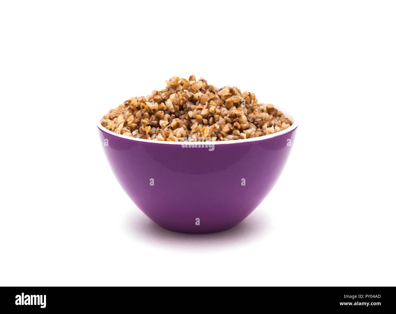 Dry buckwheat in purple ceramic bowl isolated on white background ...