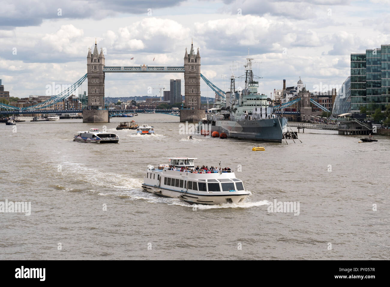 A passenger ferry sails on the river Thames with Tower Bridge and HMS ...