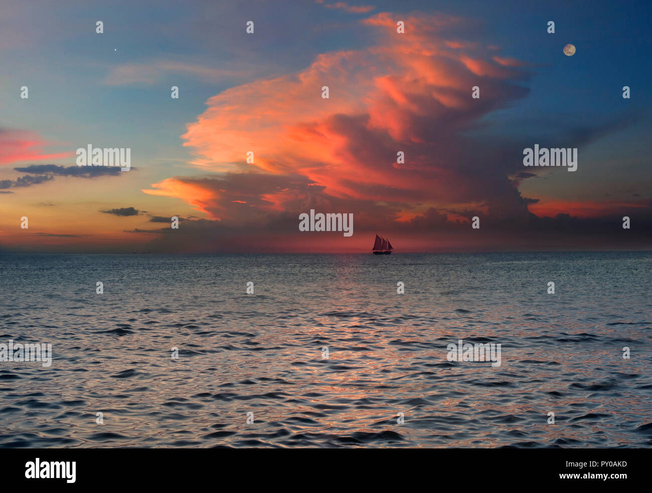 Distant view of sloop in sea under moody sky at sunset, Boracay, Aklan ...