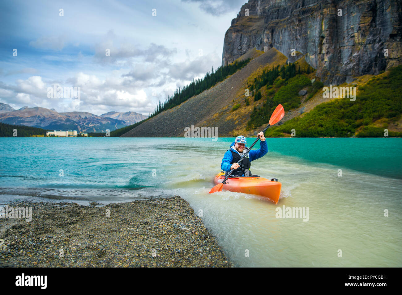 Male kayaker paddling by riverbank on glacial river, Lake Louise ...