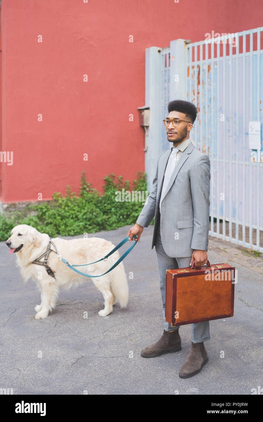 young black business man walking to work outdoor with dog on a leash ...