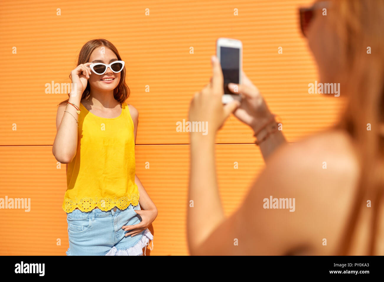 teenage girl photographing friend by smartphone Stock Photo - Alamy