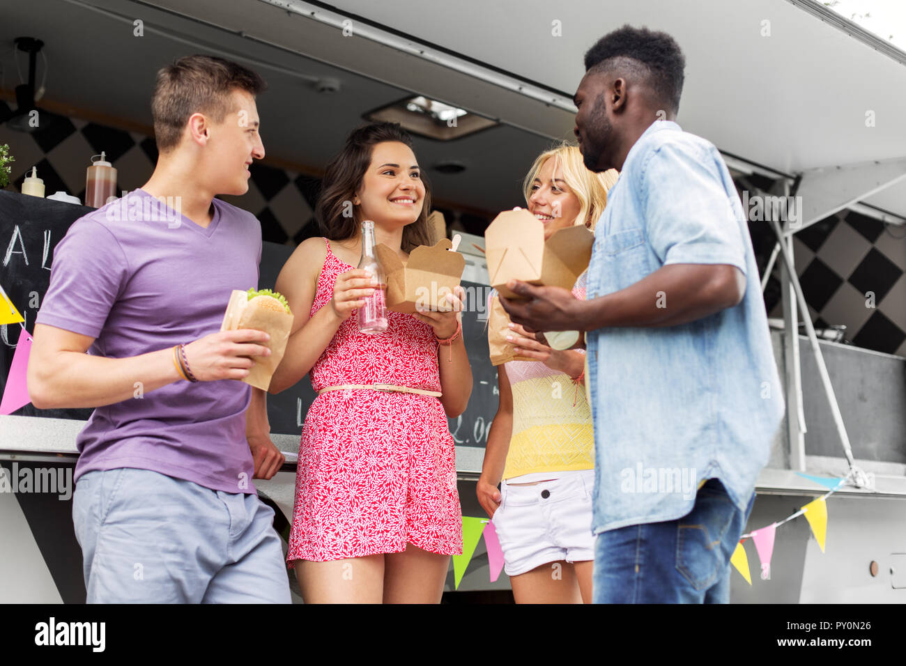 happy friends with drinks eating at food truck Stock Photo - Alamy