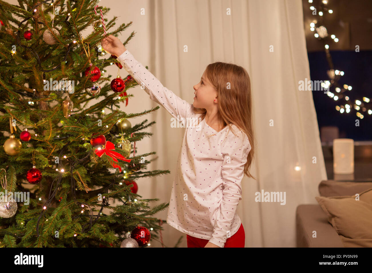 happy girl in red dress decorating christmas tree Stock Photo - Alamy
