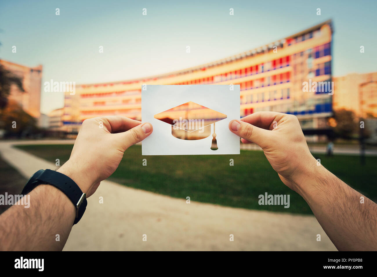 Close up of man hands holding a white paper sheet with academic cap ...