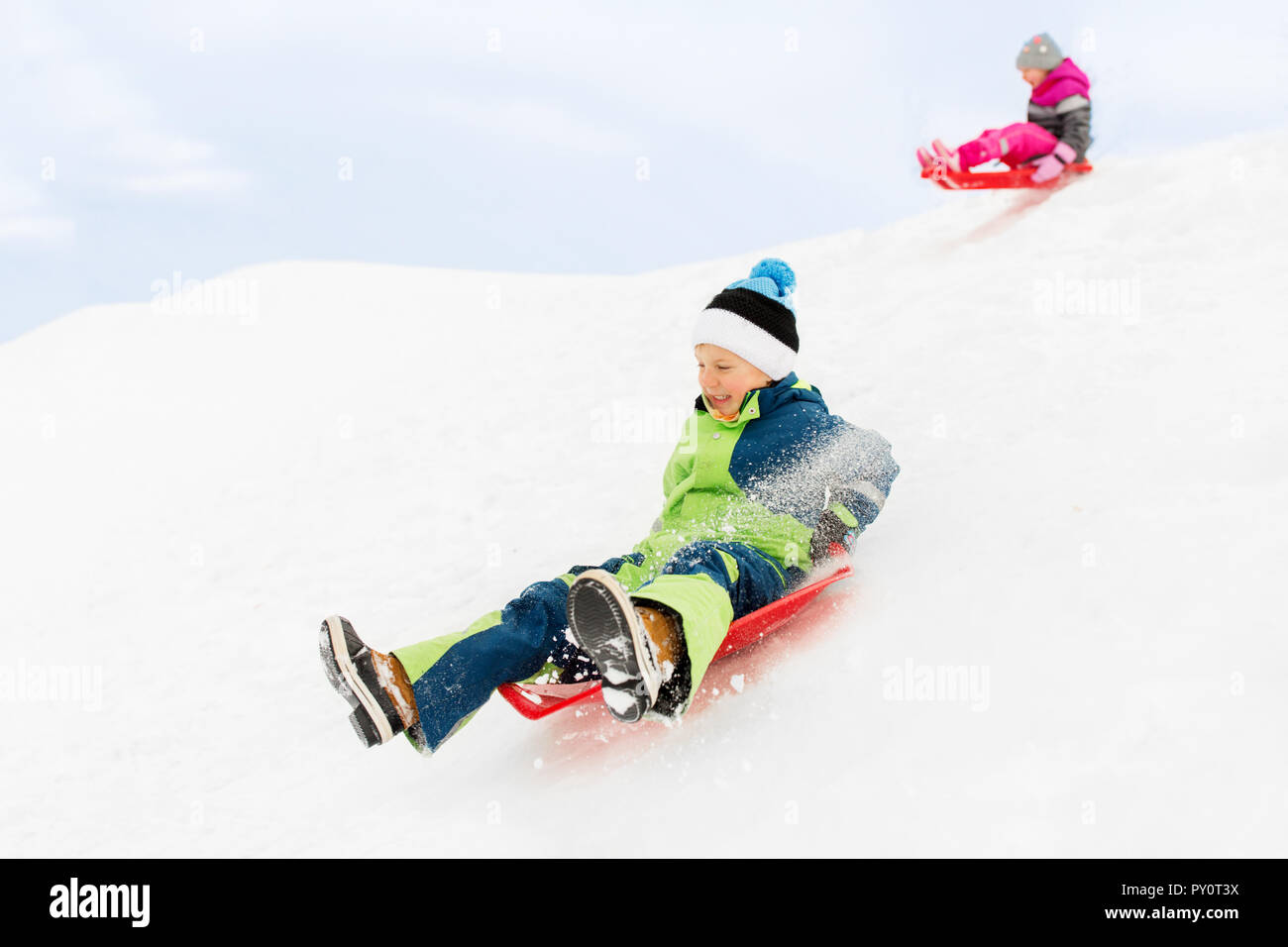 happy kids sliding on sleds down hill in winter Stock Photo - Alamy
