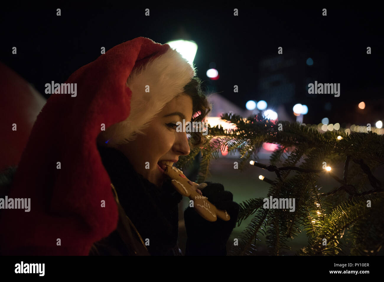 Smiling woman wearing a santa hat eating a gingerbread man Stock Photo ...