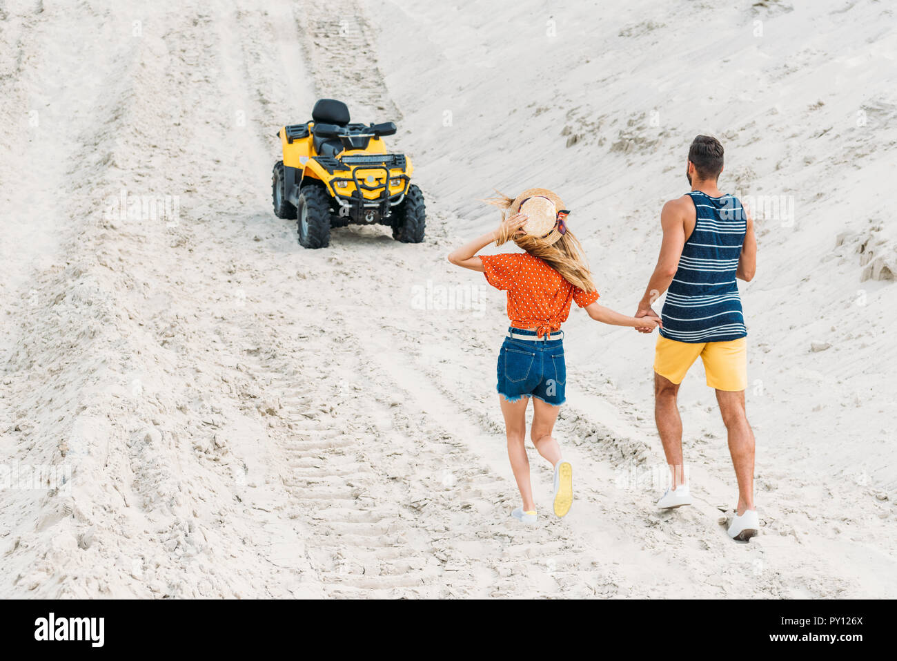 rear view of young couple going to ATV by sandy dune Stock Photo - Alamy