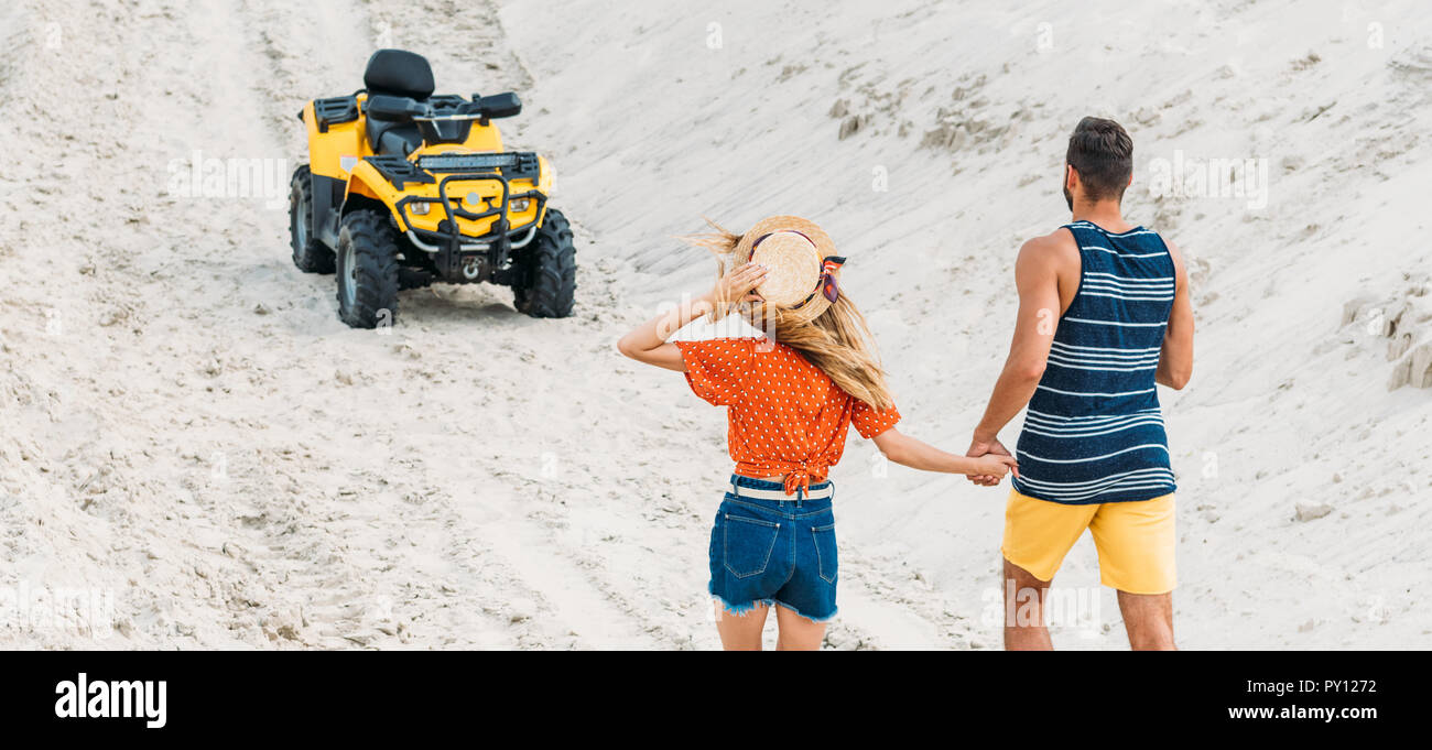 rear view of young couple going to ATV by sandy road Stock Photo - Alamy