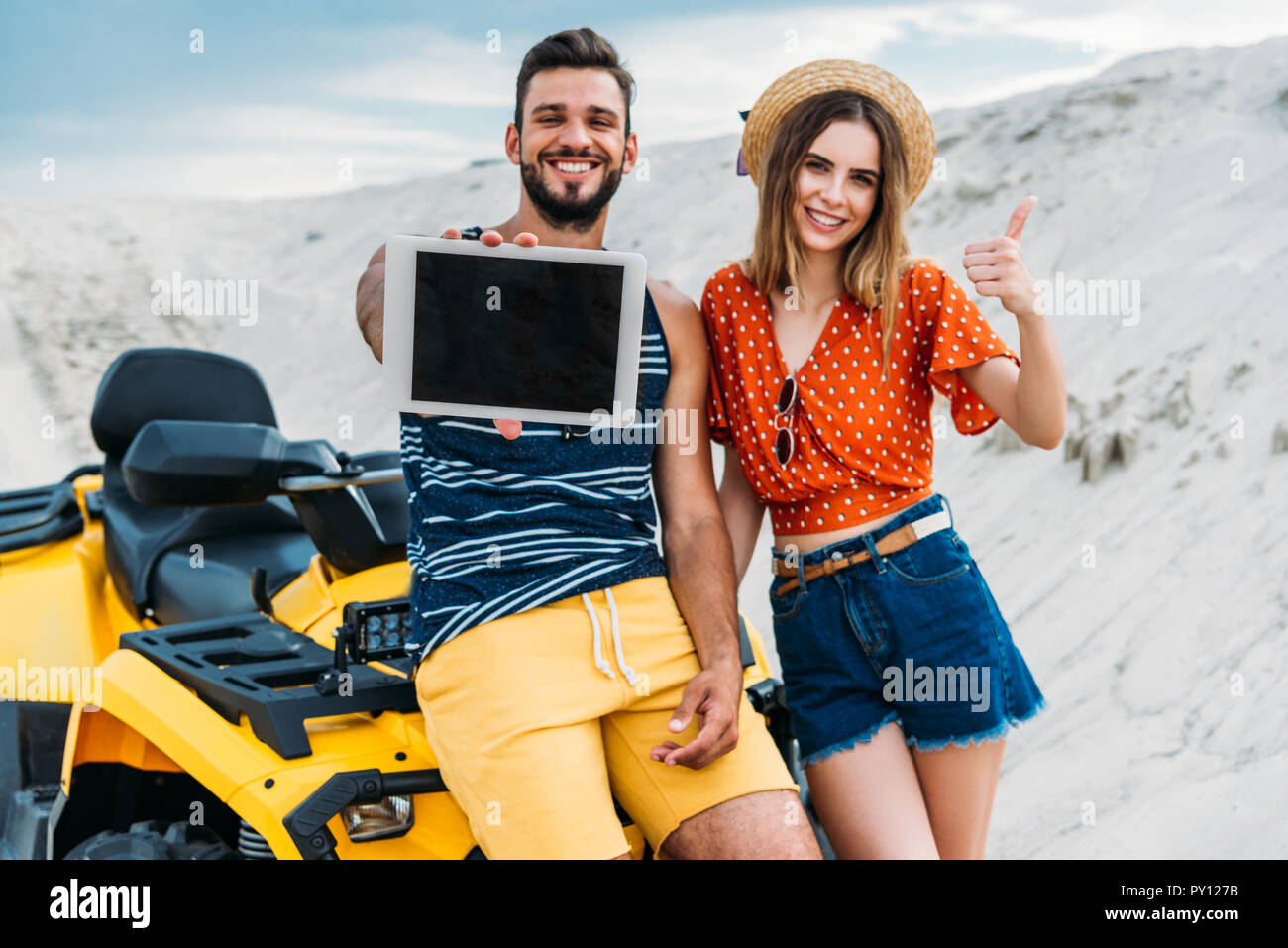 smiling young couple with atv showing digital tablet with blank screen ...