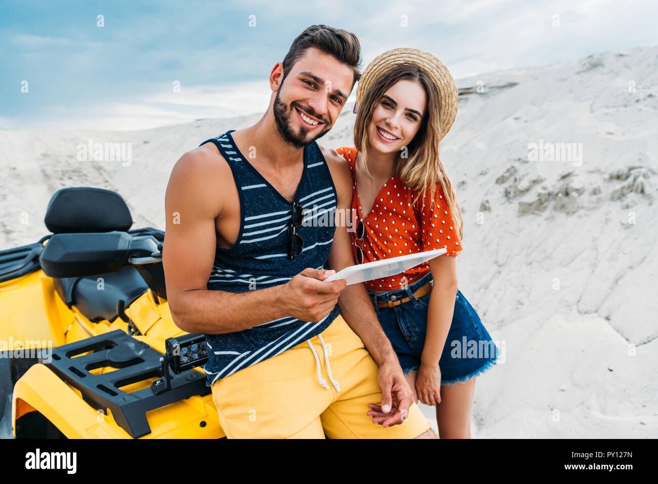 happy young couple with ATV using digital tablet in desert and looking ...
