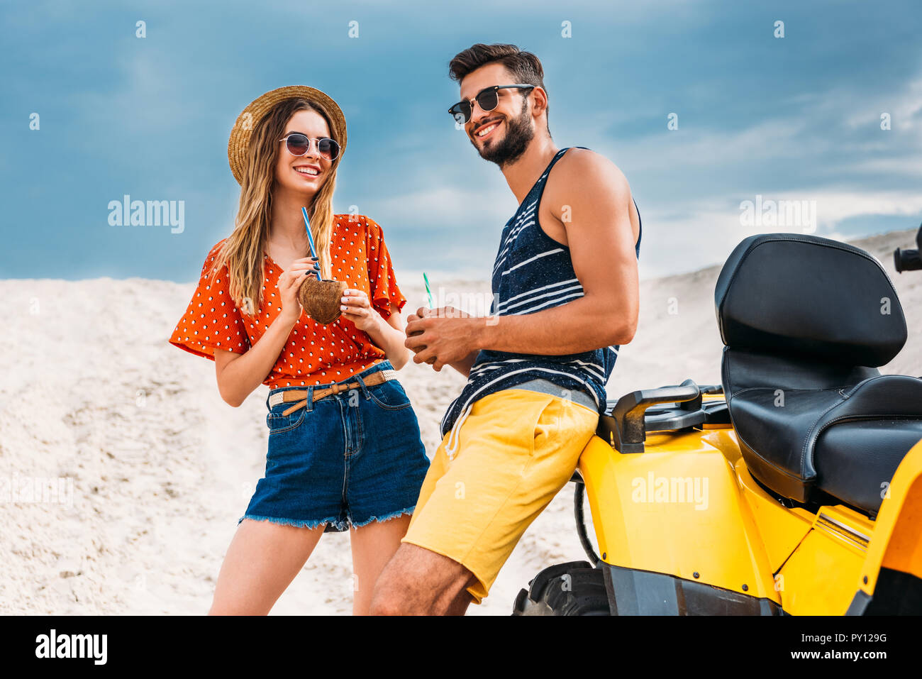 happy young couple with atv and coconut cocktails in desert Stock Photo ...