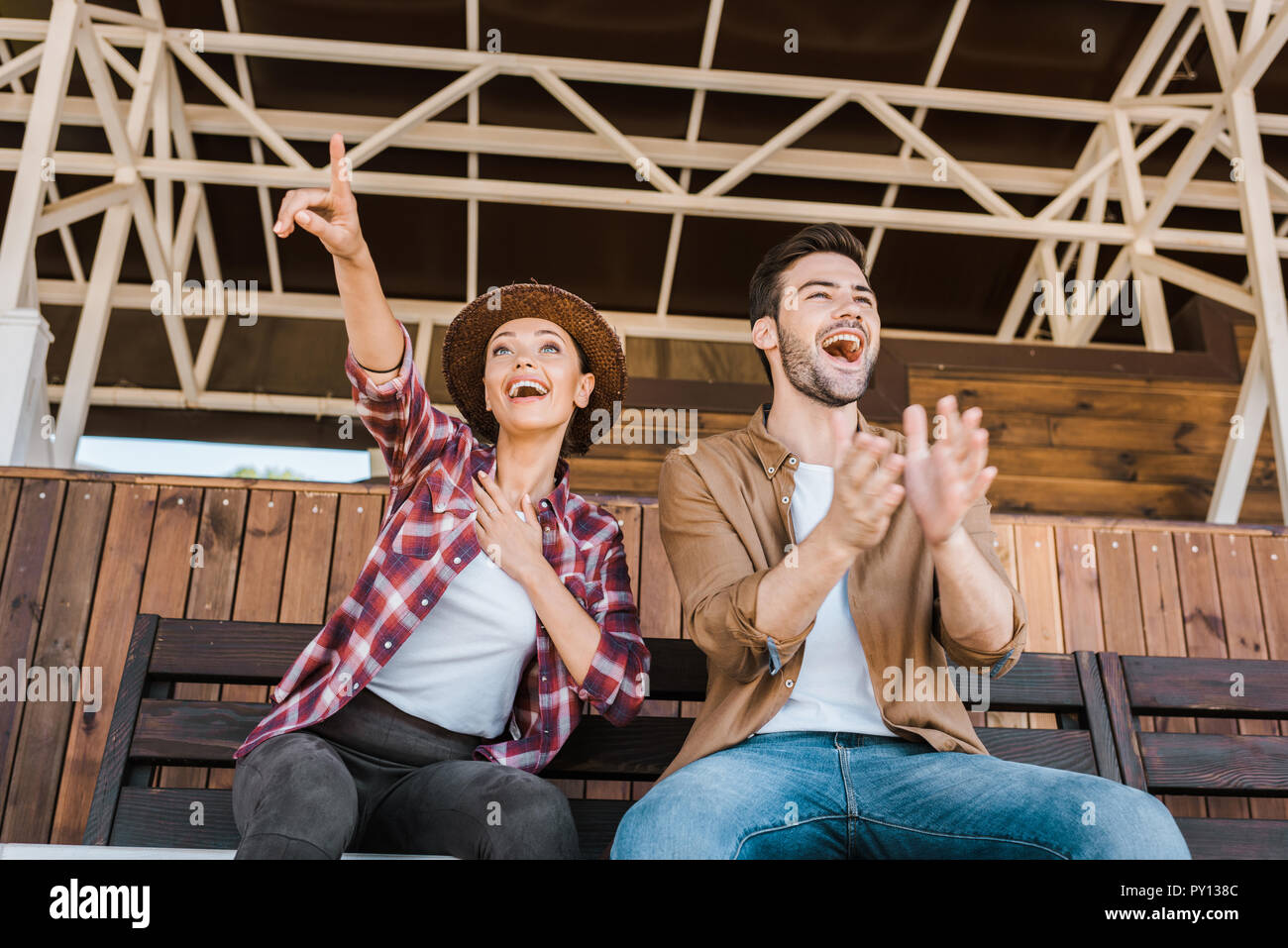 excited fans in casual clothes sitting on bench at ranch stadium and ...