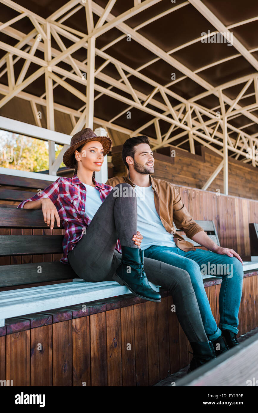 cowboy and cowgirl sitting on bench at ranch stadium and looking away ...