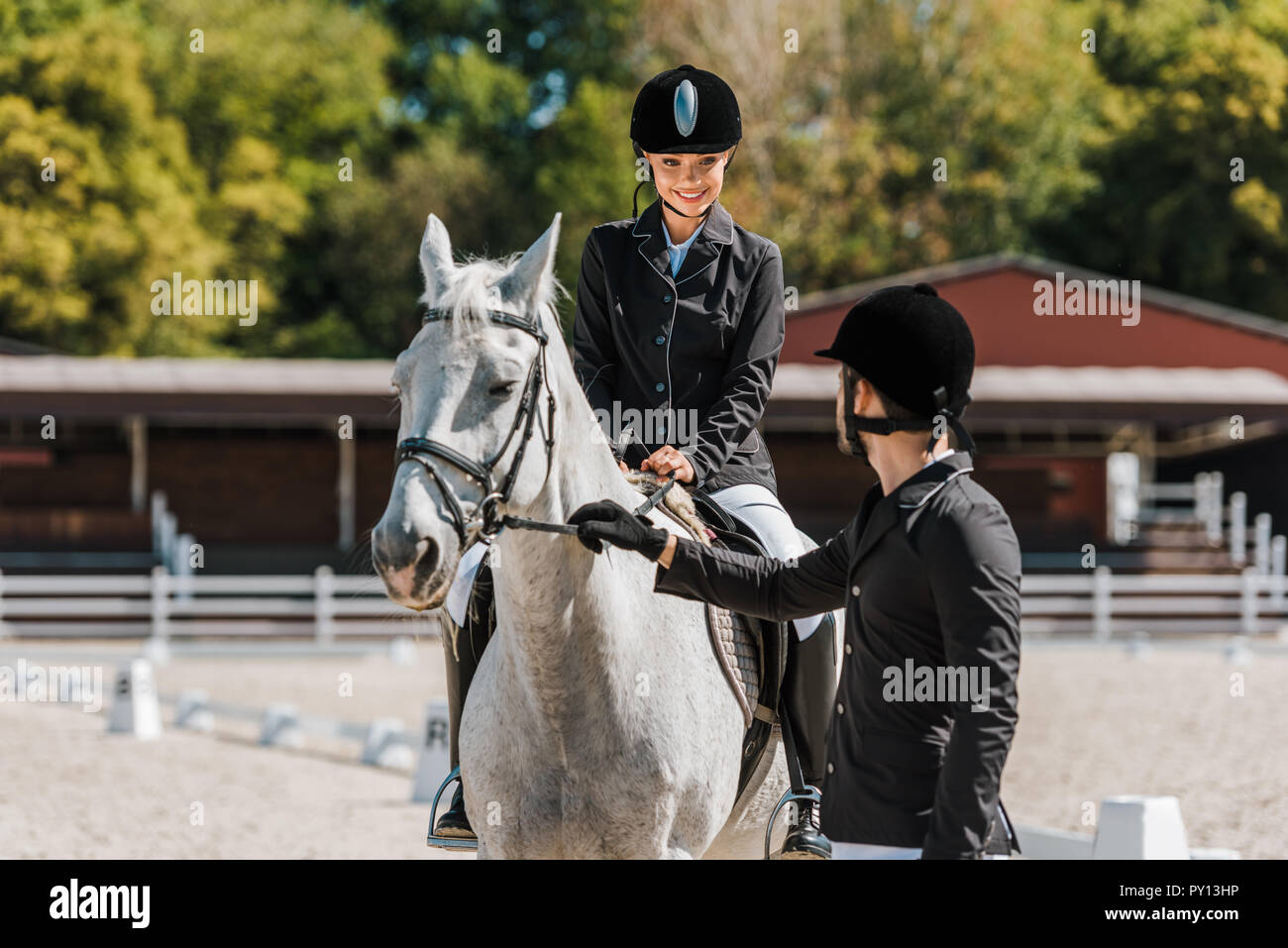 male equestrians holding horse halter, female jockey sitting on horse ...