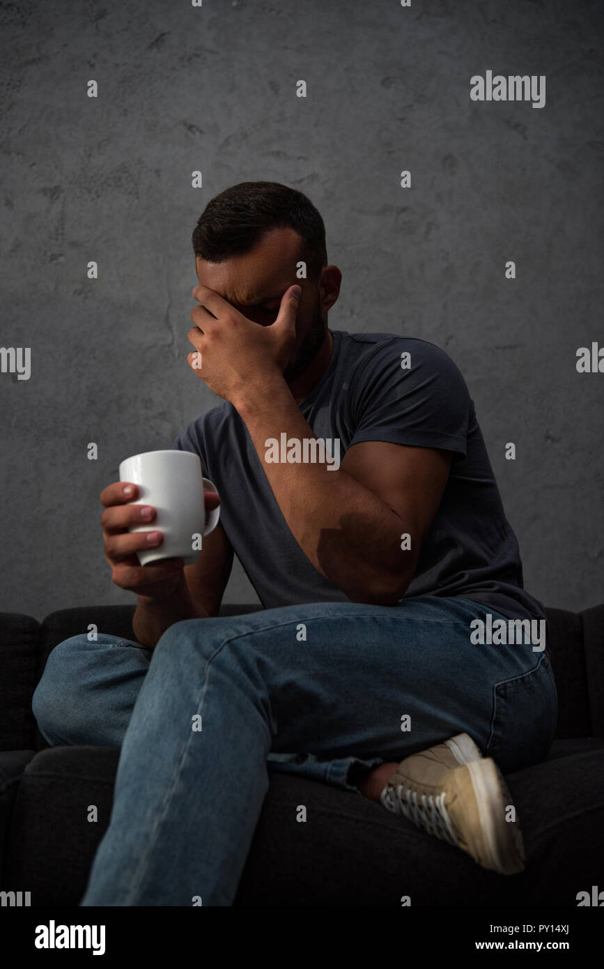 depressed crying man holding cup of coffee sitting at home Stock Photo ...