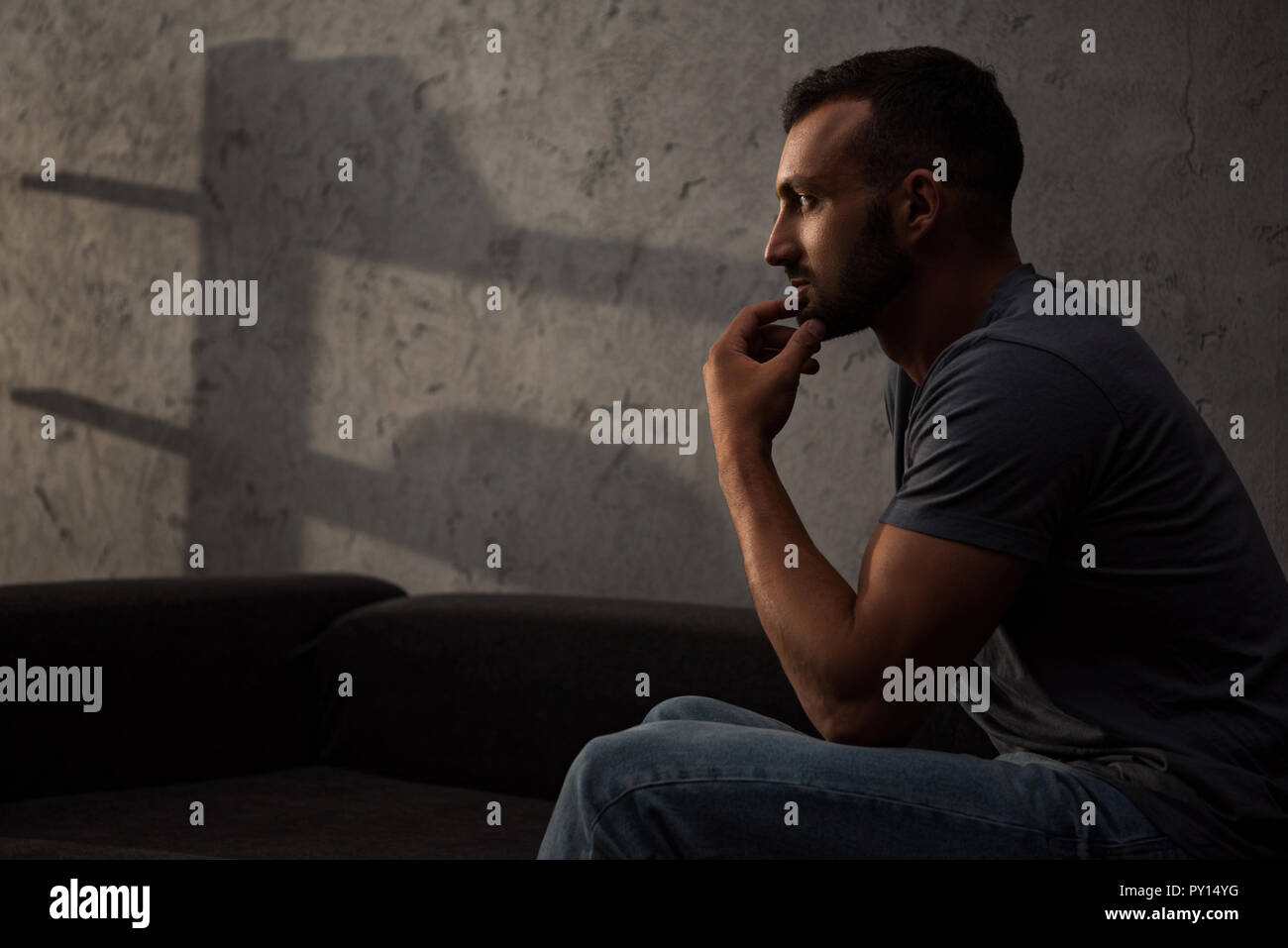 upset thoughtful man sitting on sofa Stock Photo - Alamy