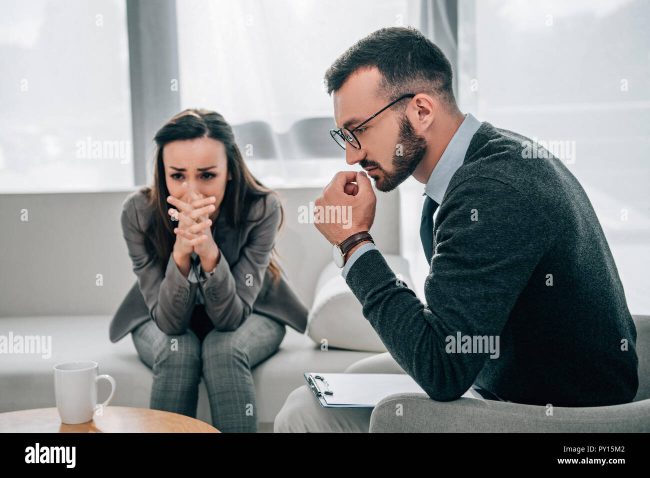 depressed patient crying and pensive psychologist sitting in doctors ...