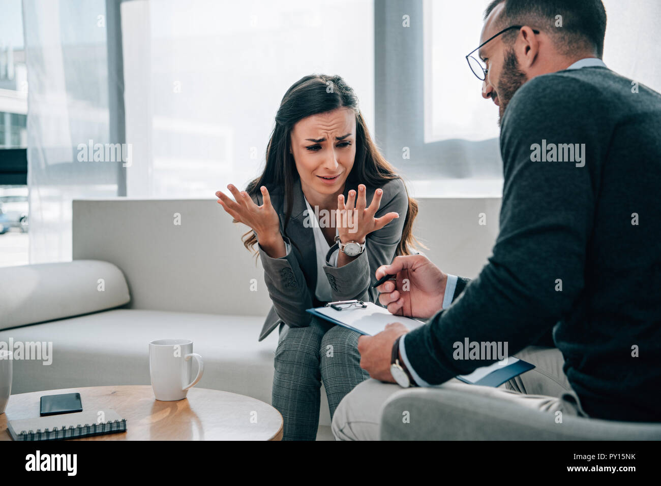 crying patient talking and psychologist taking notes in doctors office ...