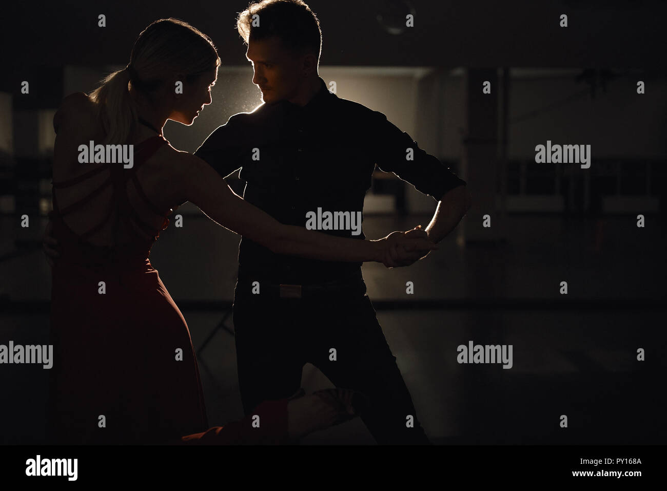 Young beautiful couple dancing with passion, light play reflected on ...