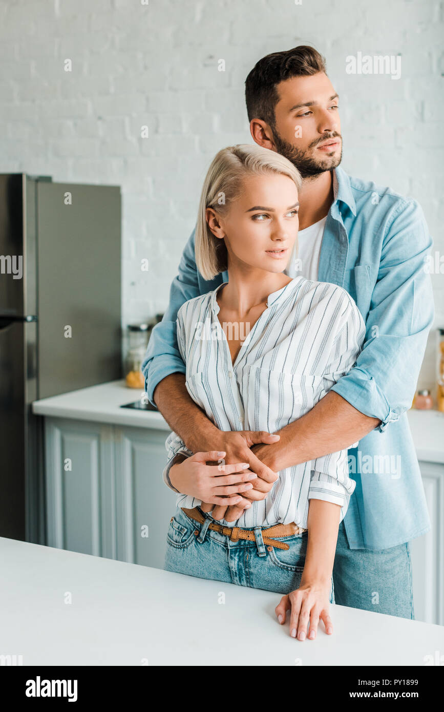 handsome boyfriend hugging girlfriend from back in kitchen and they ...