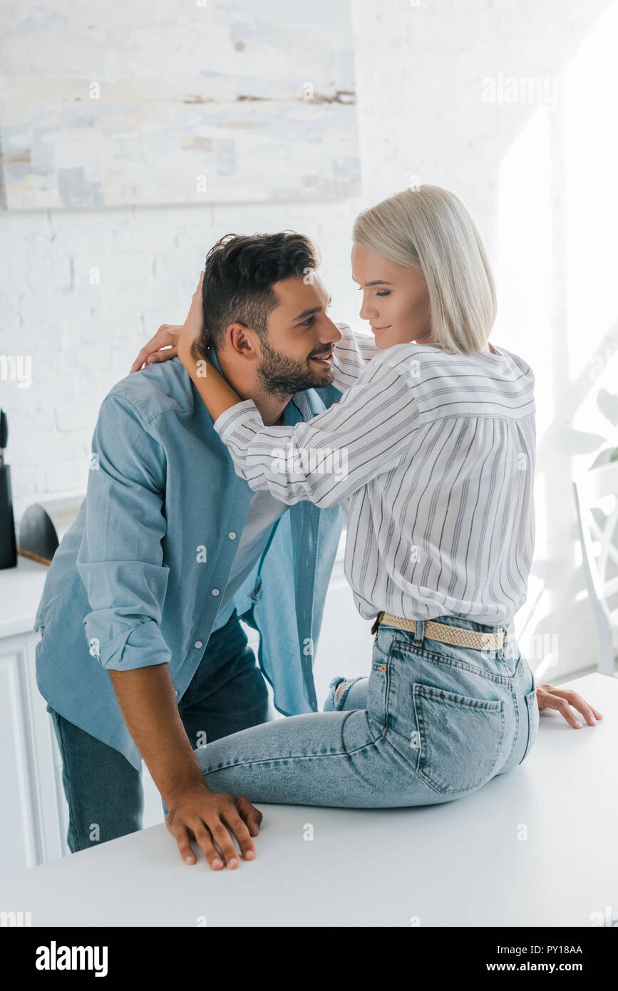 attractive girlfriend sitting on kitchen counter and hugging handsome ...